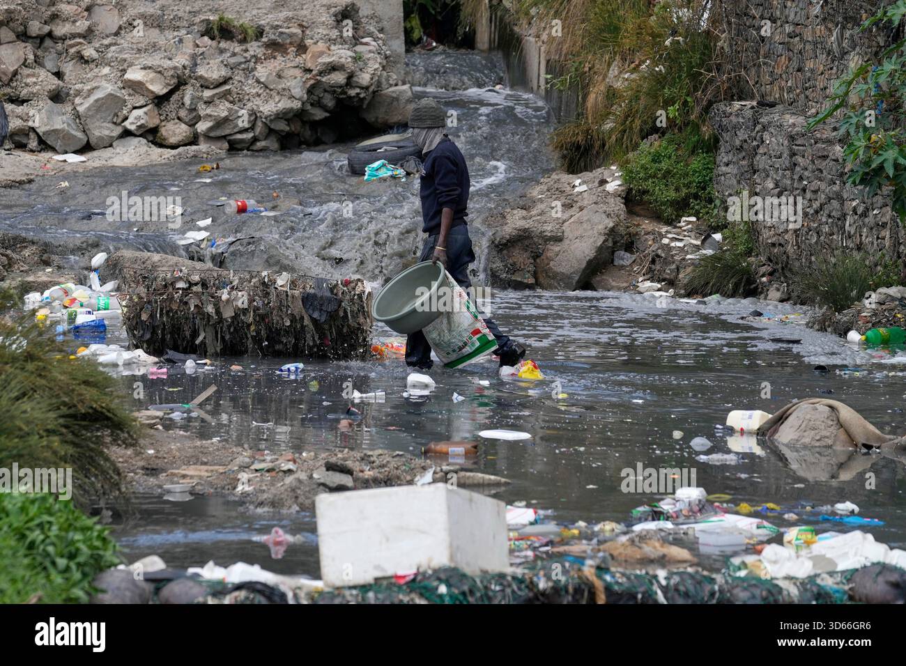 A man looks for scrap material on a polluted Jukskei River in the ...