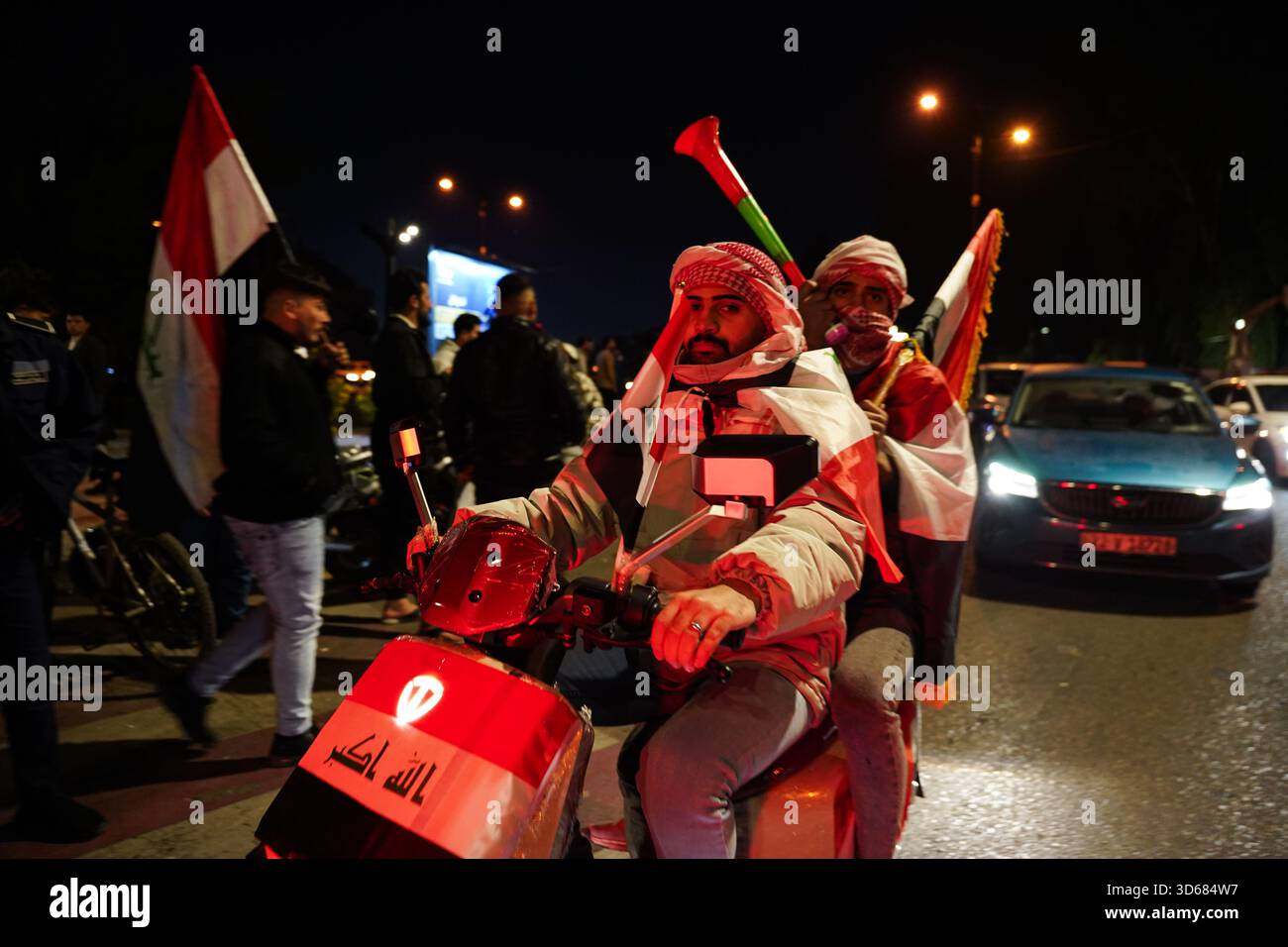 Iraqis ride motorcycle hanging flag as they celebrate following Iraq’s ...