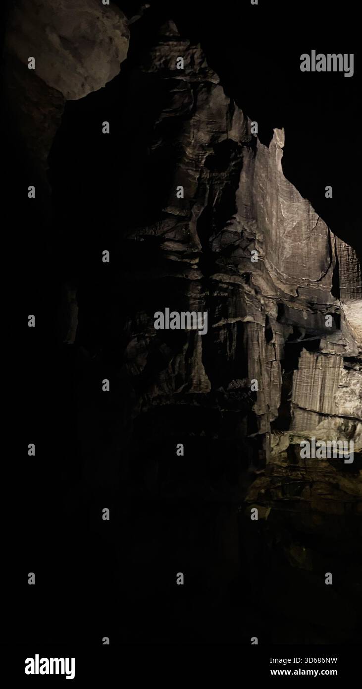 Dark cave walls lit by subtle light reveal rugged limestone formations ...