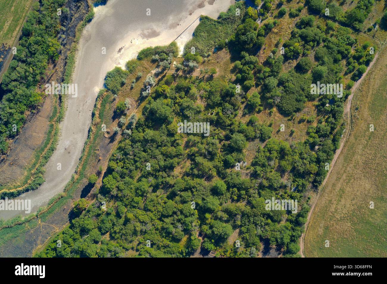Top-down aerial photo showing a wide, dry, winding riverbed of pale ...