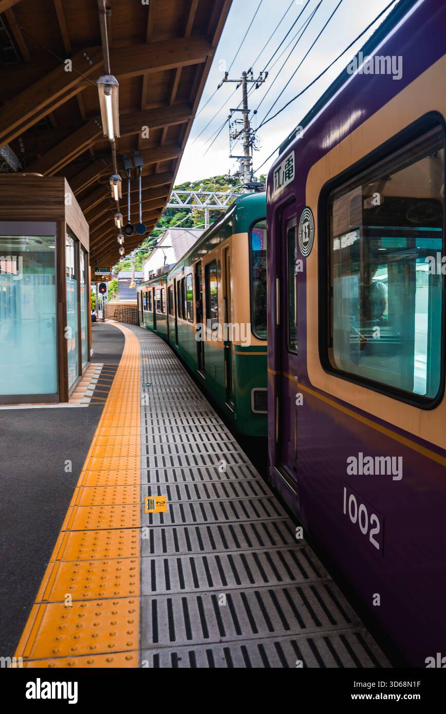 Enoden trains pass on a curved narrow platform in Kamakura, Japan Stock ...