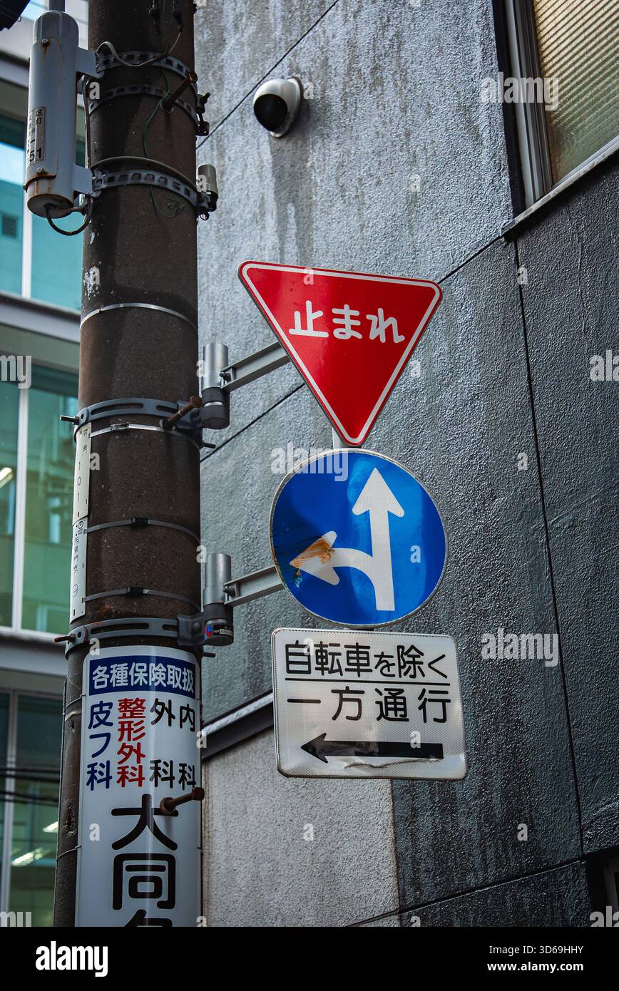 Tokyo utility pole with layered Japanese road signs on city street ...