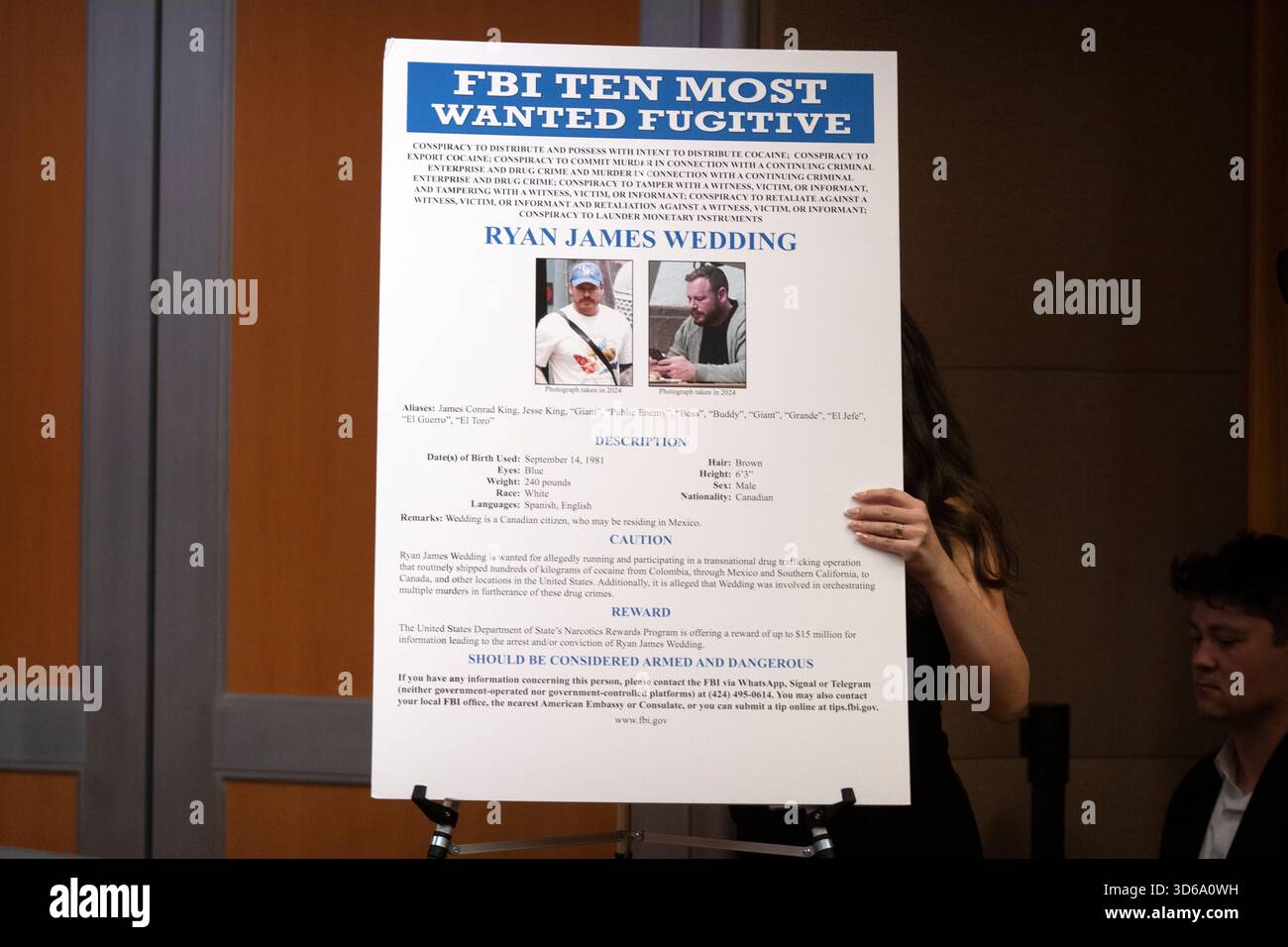 A staff member moves a wanted poster for Canadian fugitive Ryan James ...