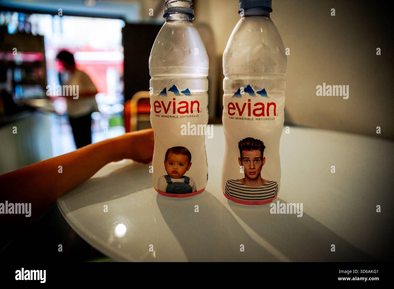 Evian water bottles with illustrated baby and adult faces displayed on ...