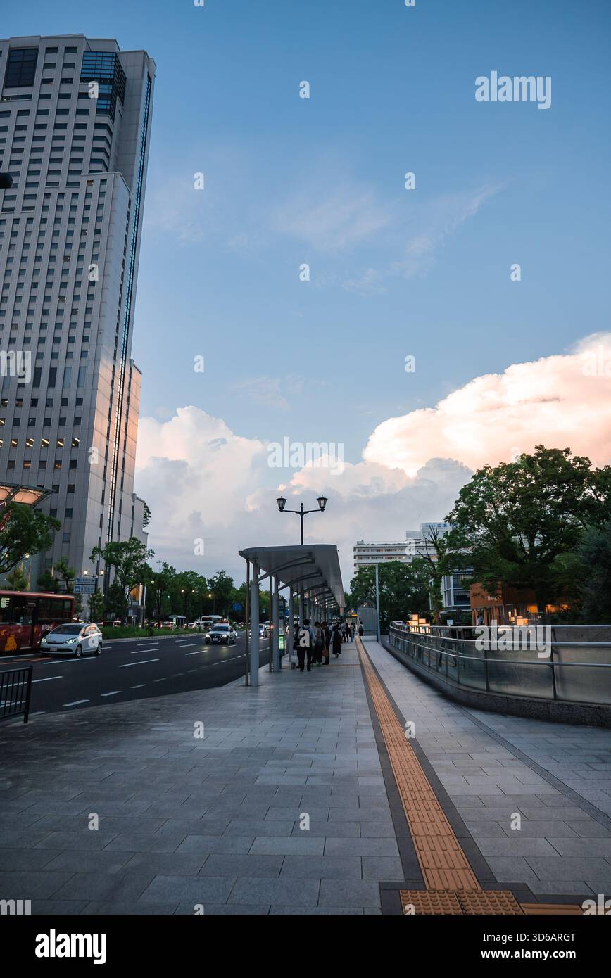 Osaka riverside street at dusk with commuters and high rise view Stock ...