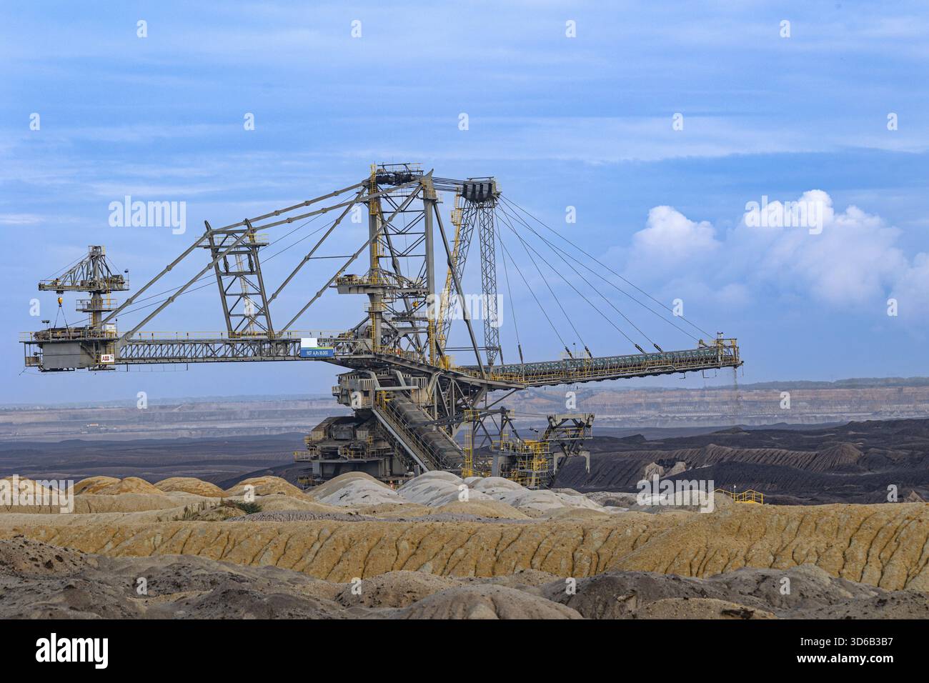 Large mining excavator in operation with wide landscape under blue sky ...