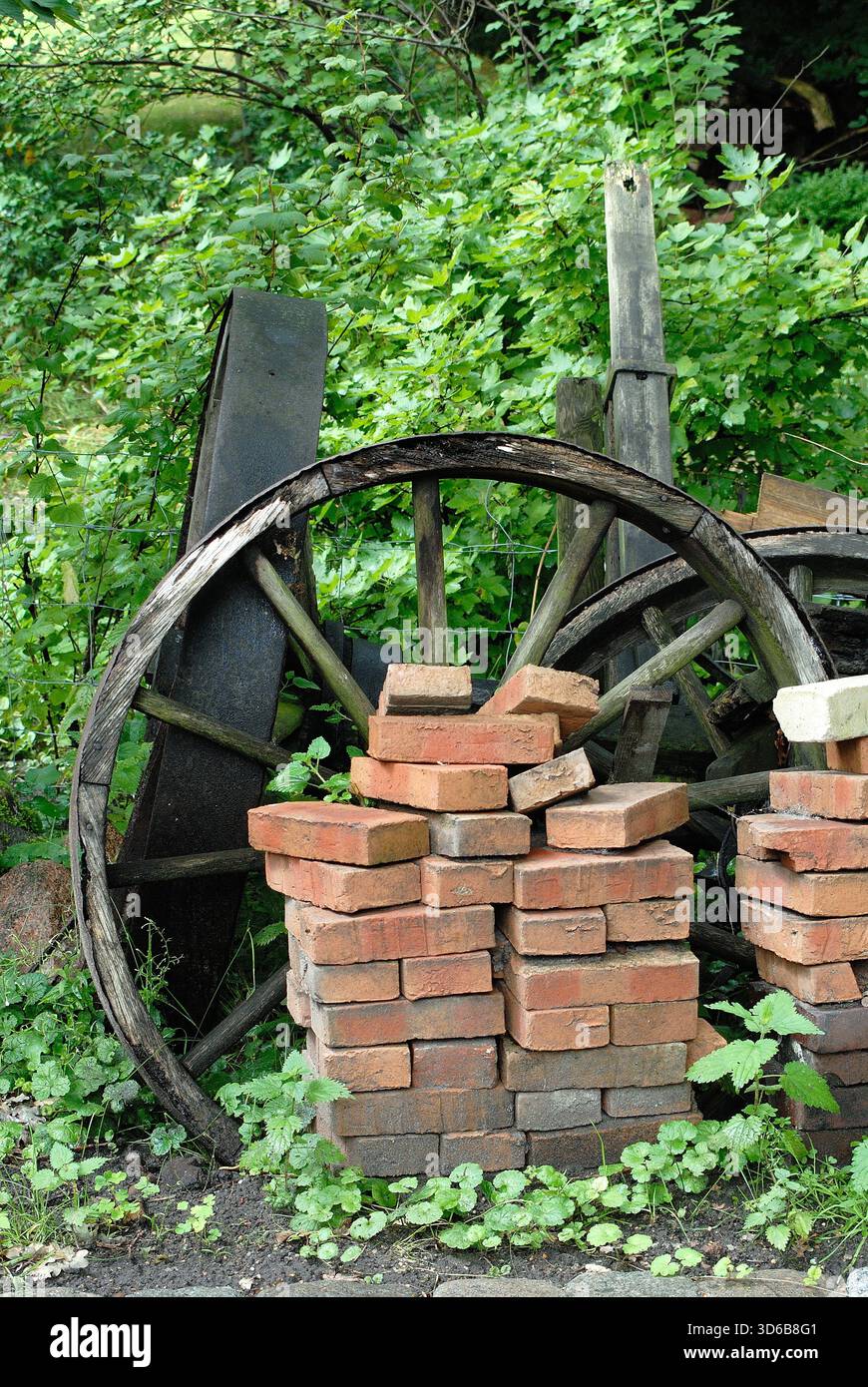 Old Wooden Wagon Wheel with Stacked Bricks in Greenery Stock Photo - Alamy
