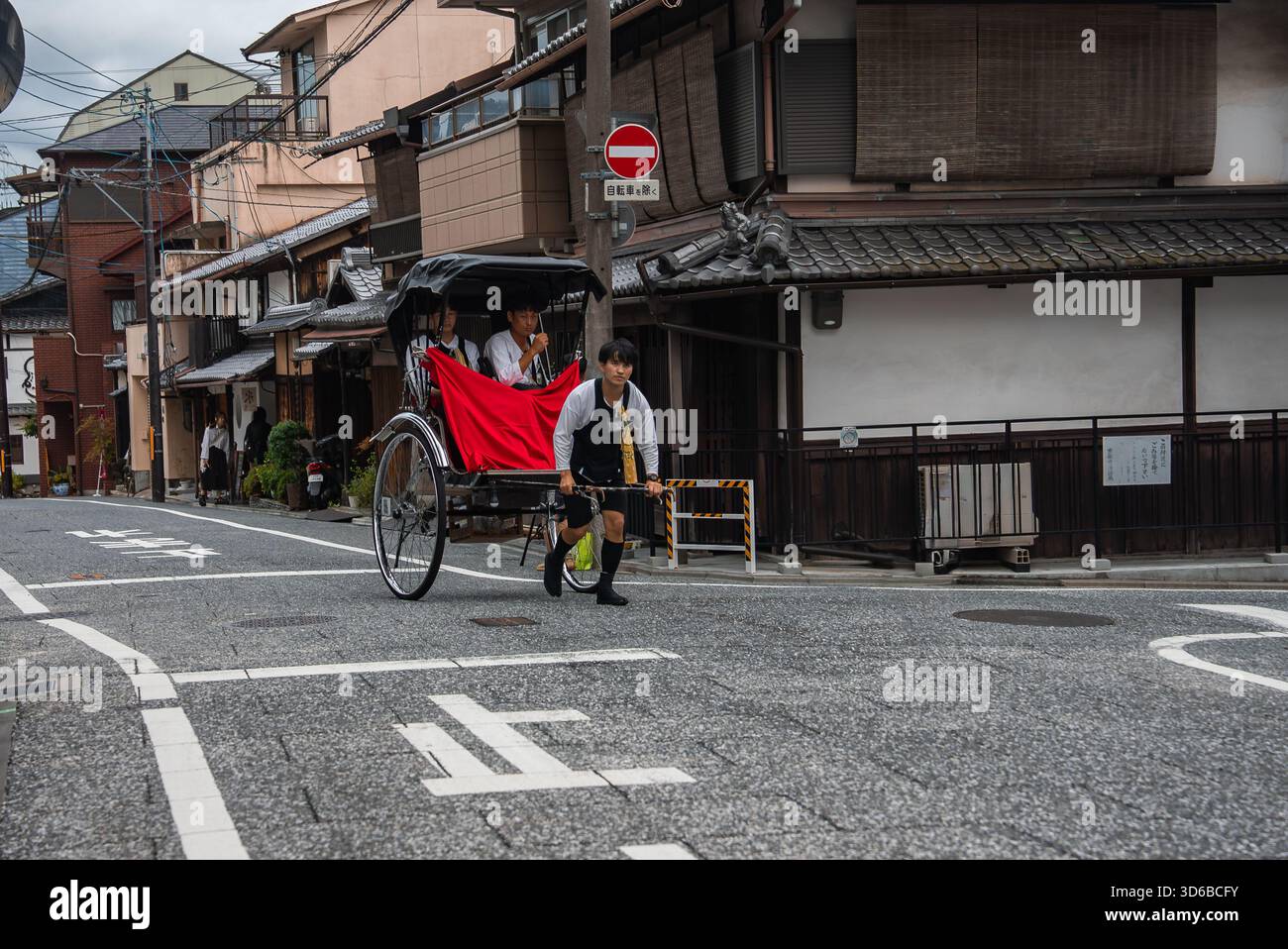 Rickshaw runner pulls jinrikisha past machiya in Kyoto historic ...