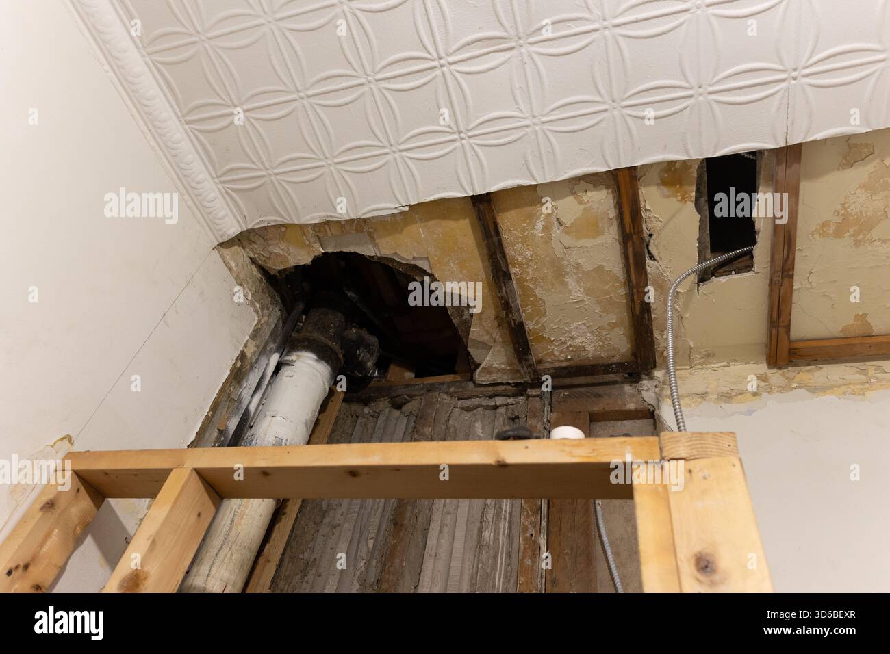 Damage to ceiling reveals exposed pipes and structural wear in ...