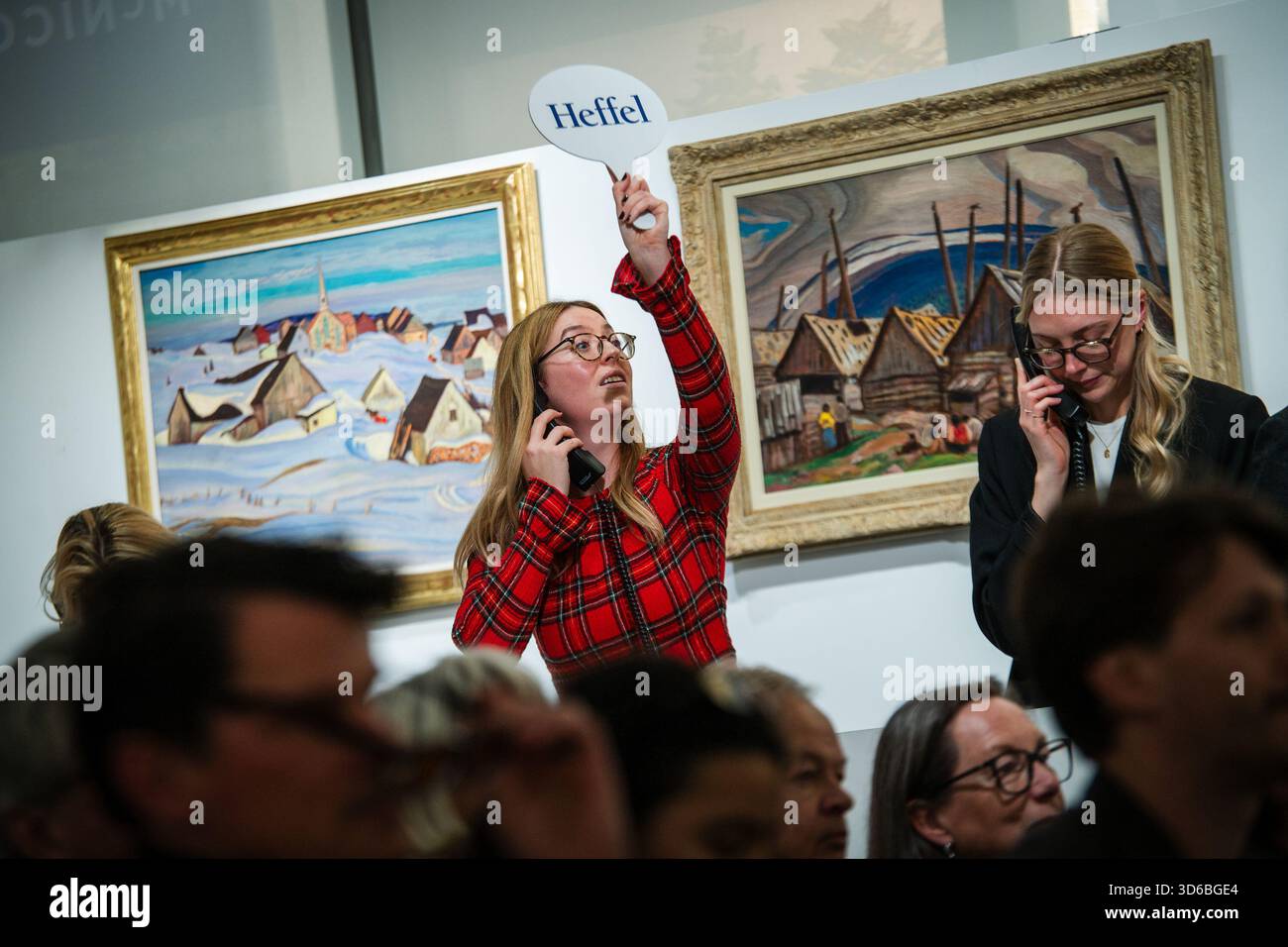 A woman works the phone during bidding in an auction for works of art ...