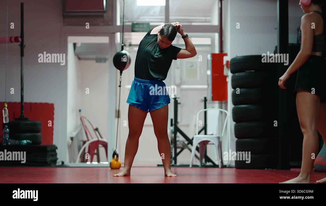 Female athlete stretching at a gym, preparing for muay thai shadow ...