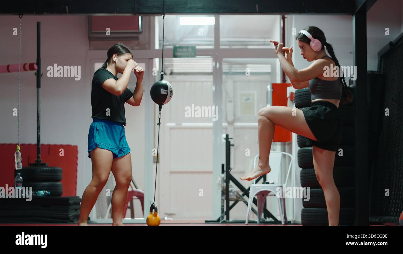 Women athletes practicing muay thai techniques and shadow boxing in gym ...