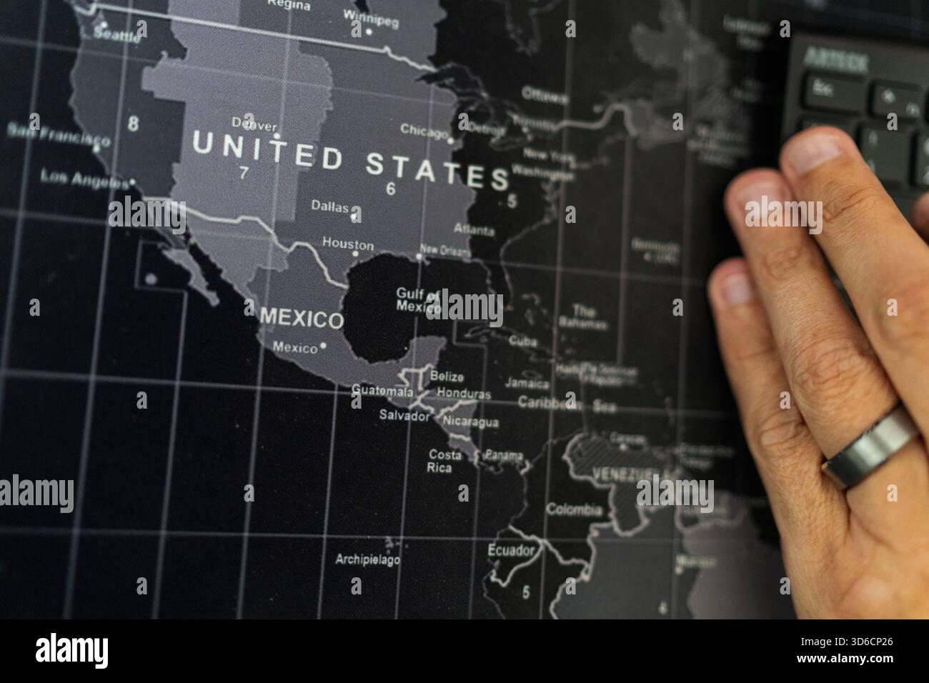 Alek Schott works on his computer next to a map showing the United ...