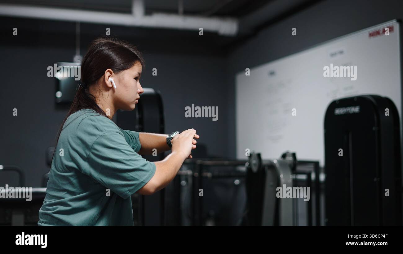 Young woman exercising squats in gym, monitoring fitness progress on ...