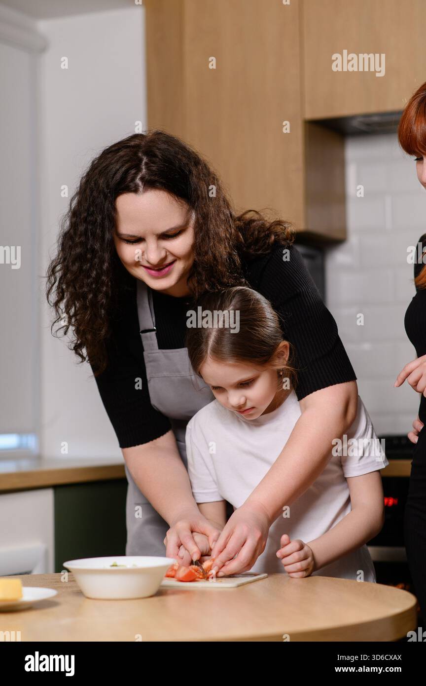 Mother and daughter bond by cooking together in kitchen. Woman helps ...