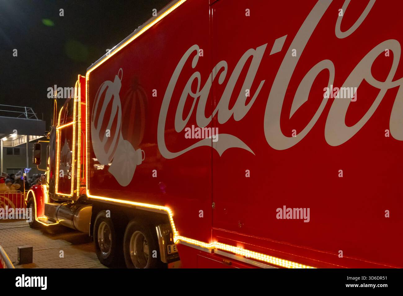 A Coca-Cola truck is illuminated by lights and stands in the parking ...