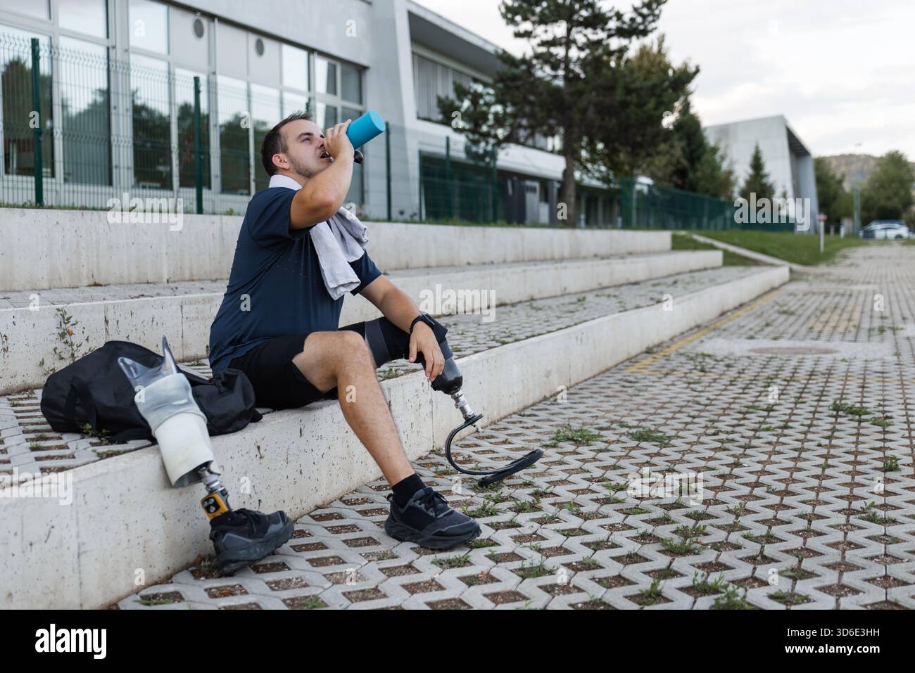 Male athlete with a disability wearing a running blade, sitting by a ...