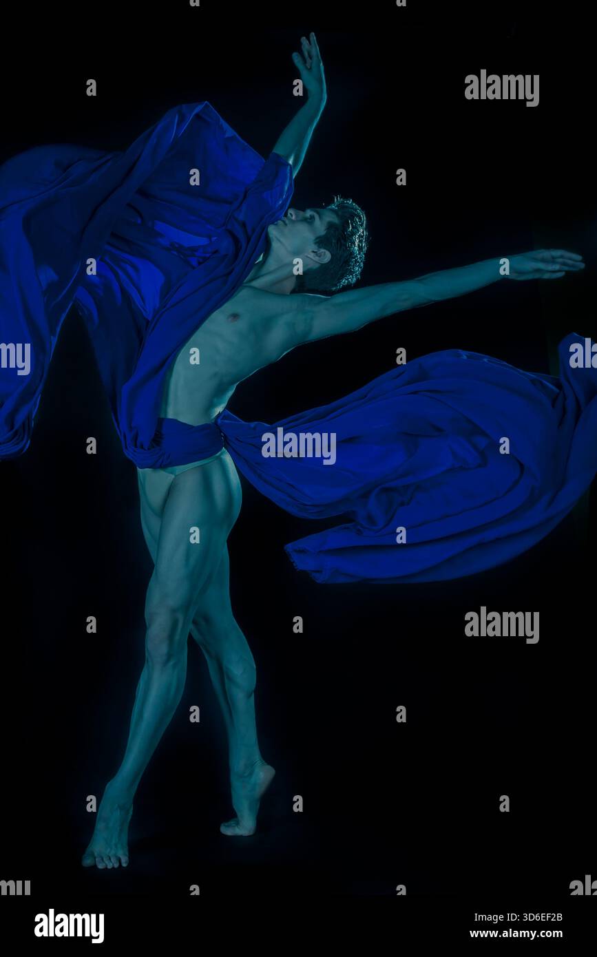 Color portrait of a male ballet dancer performing an elegant classical pose in a studio setting ...