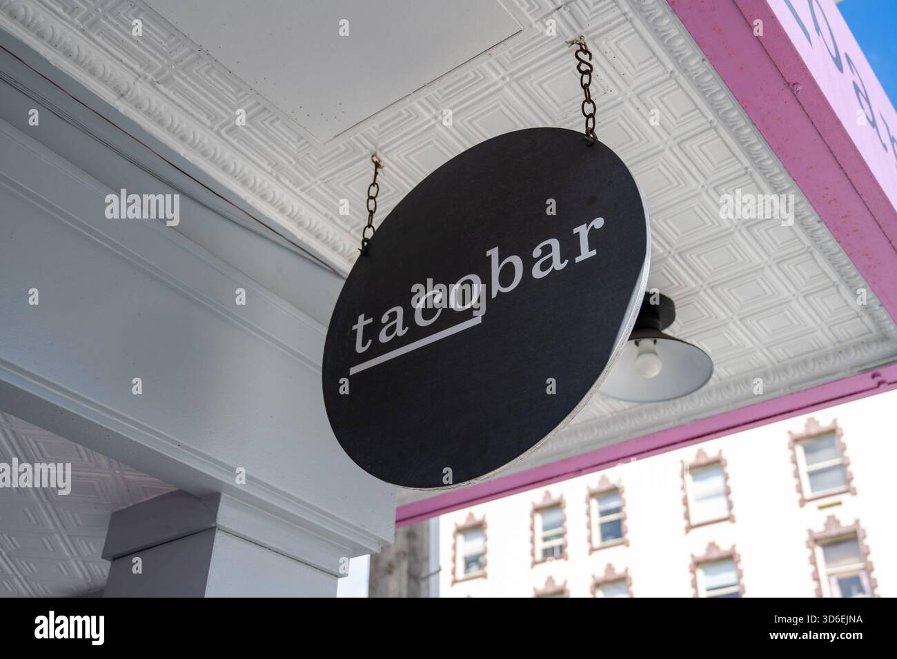Round hanging sign reading "tacobar" under pressed tin ceiling and pink ...