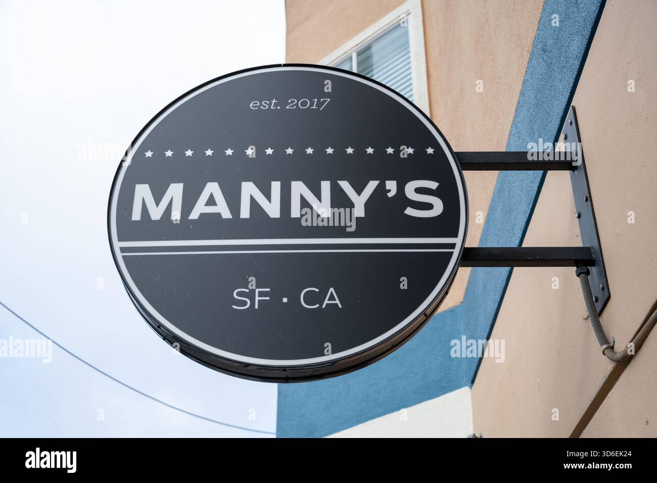 Round hanging business sign reading "MANNY'S" on a building exterior on ...