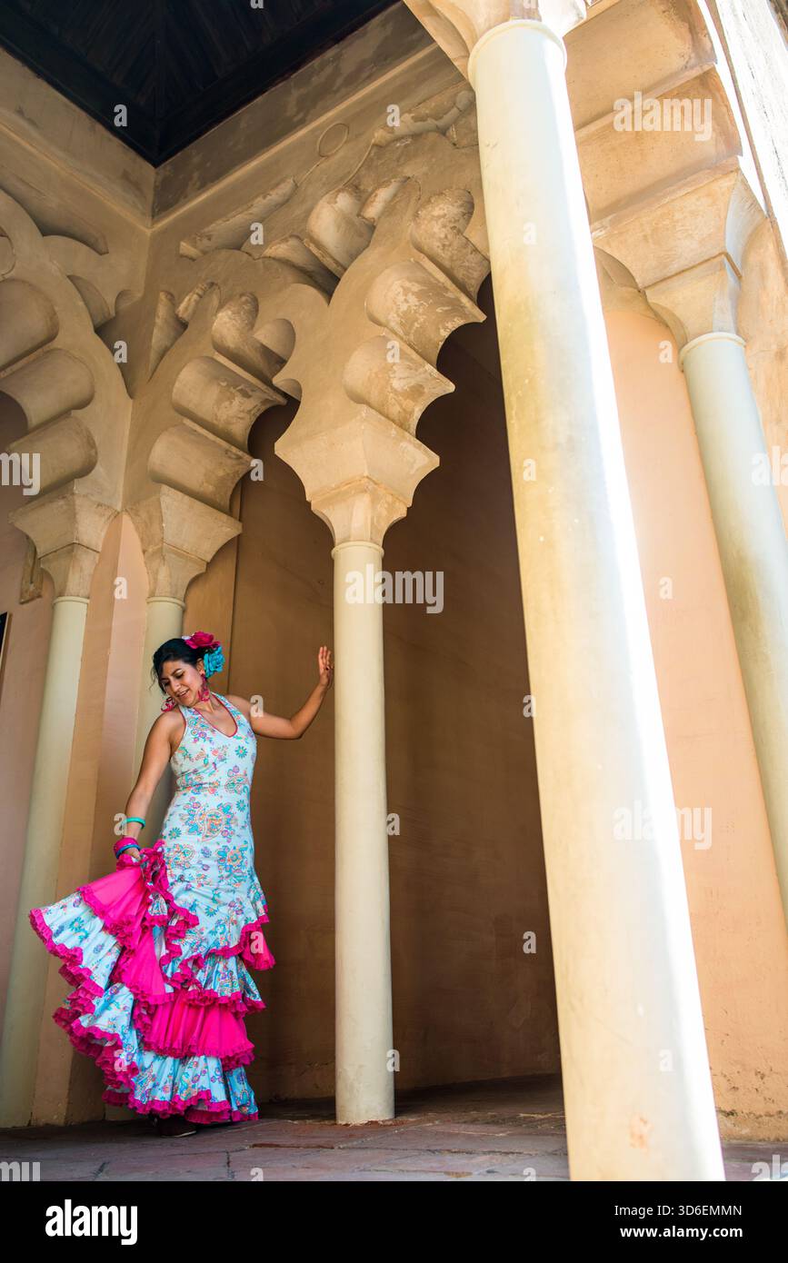 A woman in a vibrant flamenco dress poses gracefully in a historic ...