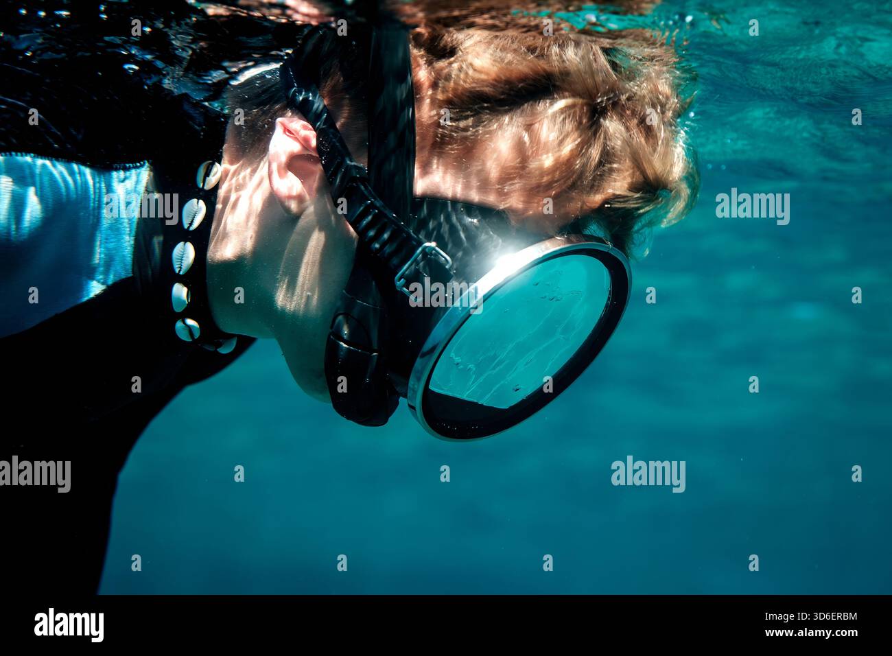 An underwater view of a diver holding a large magnifying glass to ...