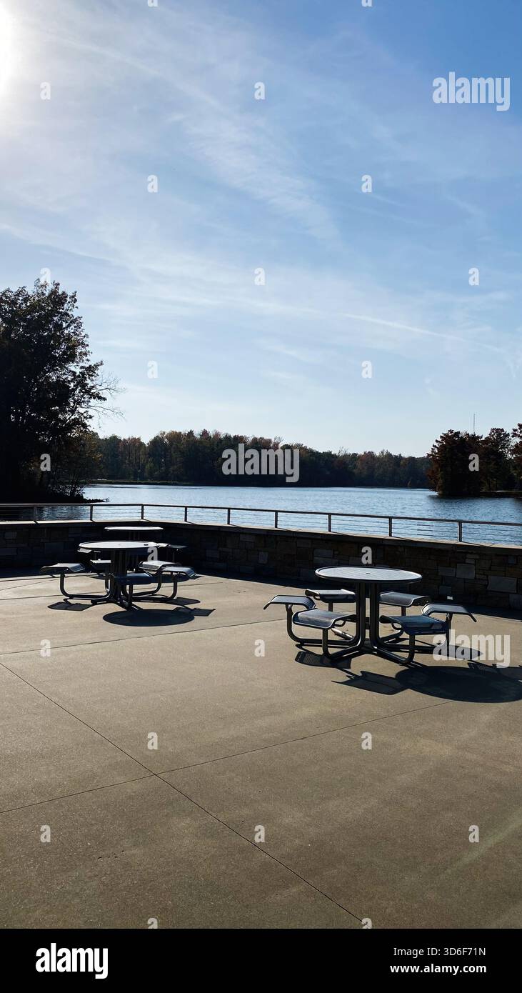 Sunny lakeside terrace with round tables invites outdoor relaxation by ...