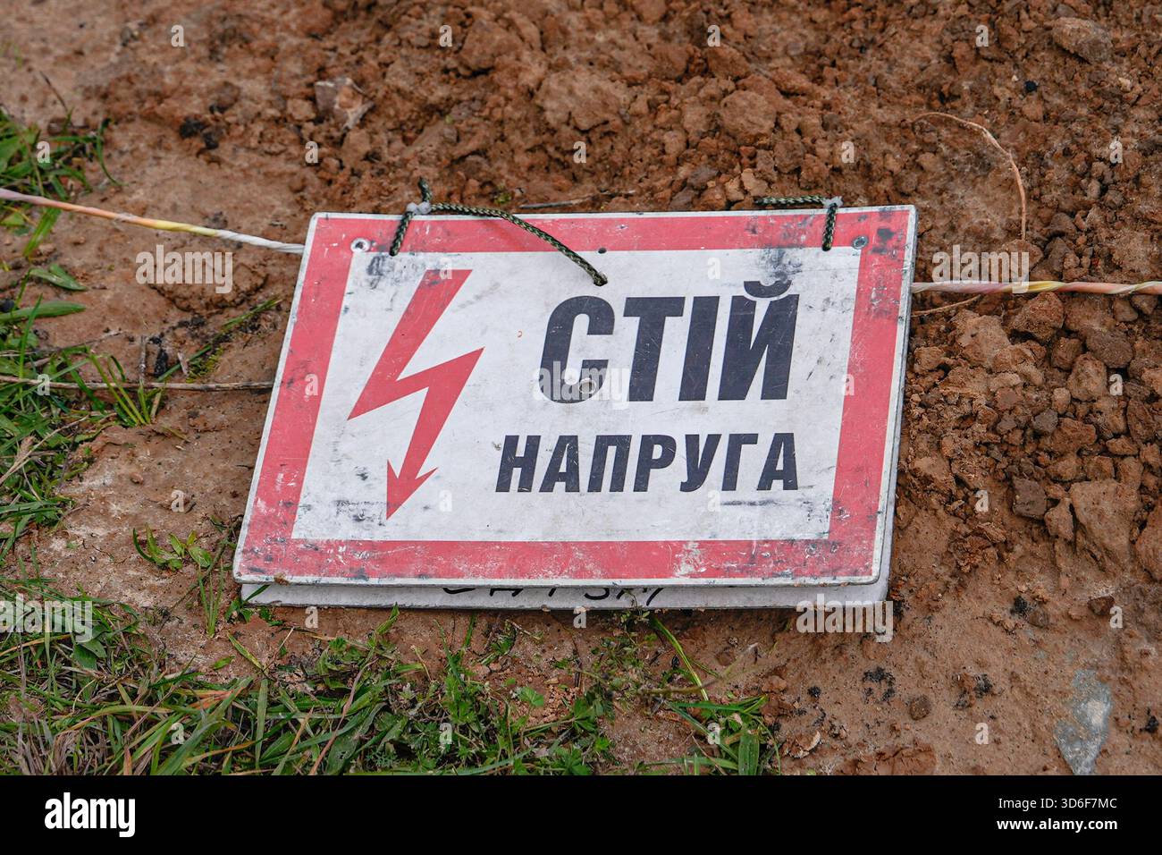 A high voltage sign lays on the ground at a damaged Chernihiv Oblenergo ...