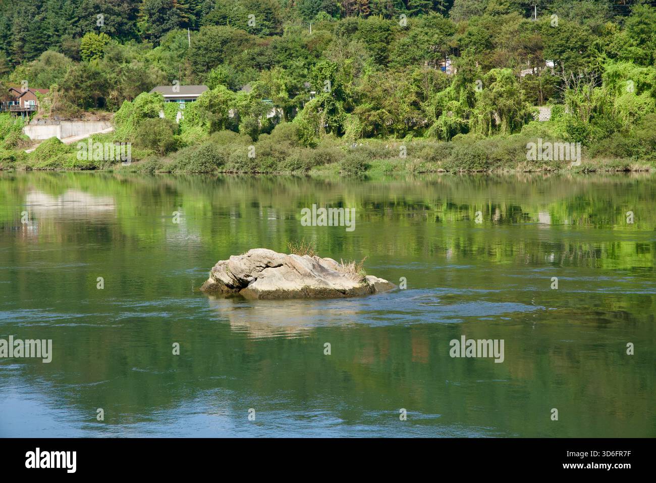 A single boulder sits in the slow current of the Bukhangang, surrounded ...