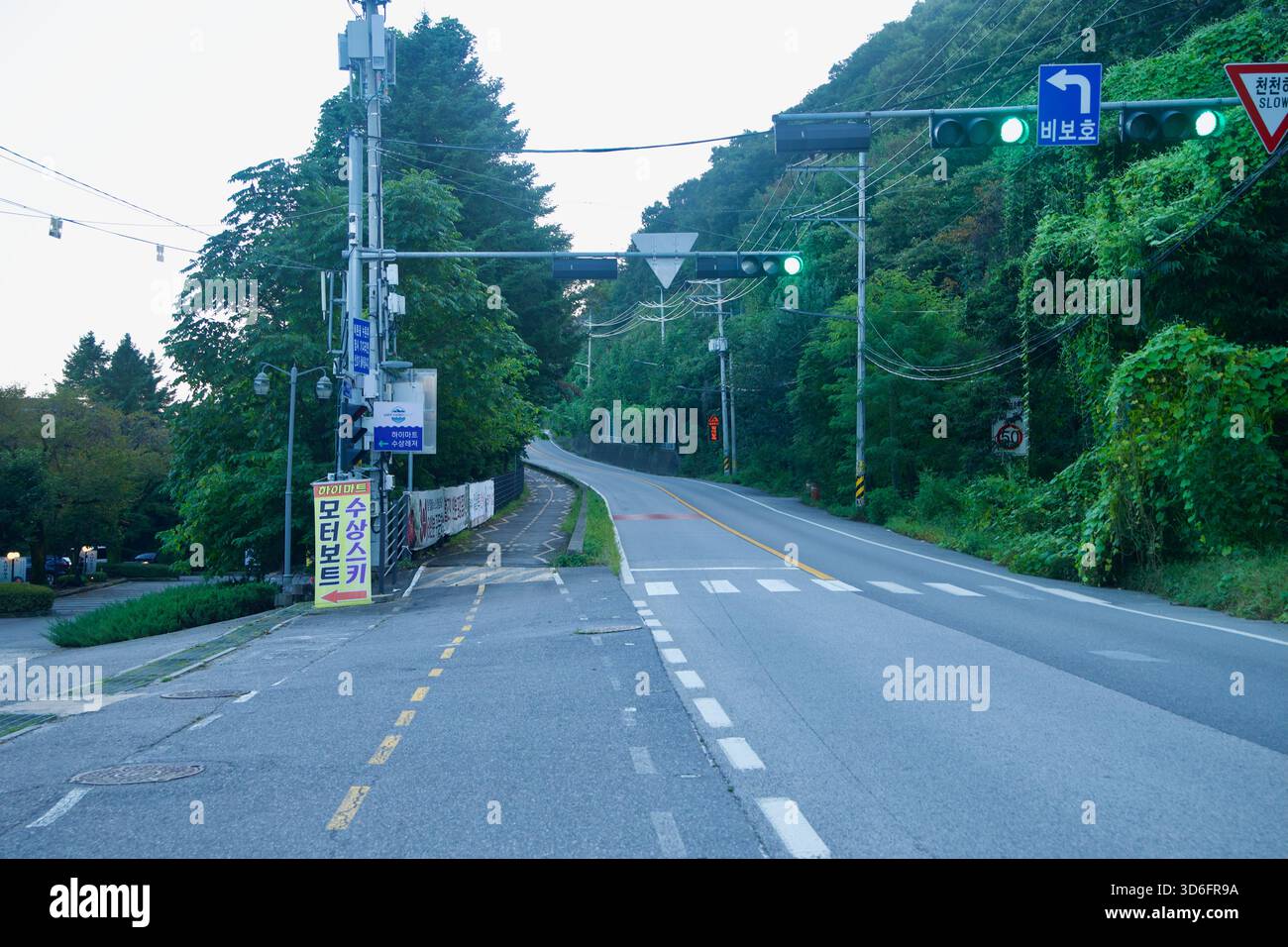 A quiet hill road in Namyangju climbs past a separated bike lane and ...