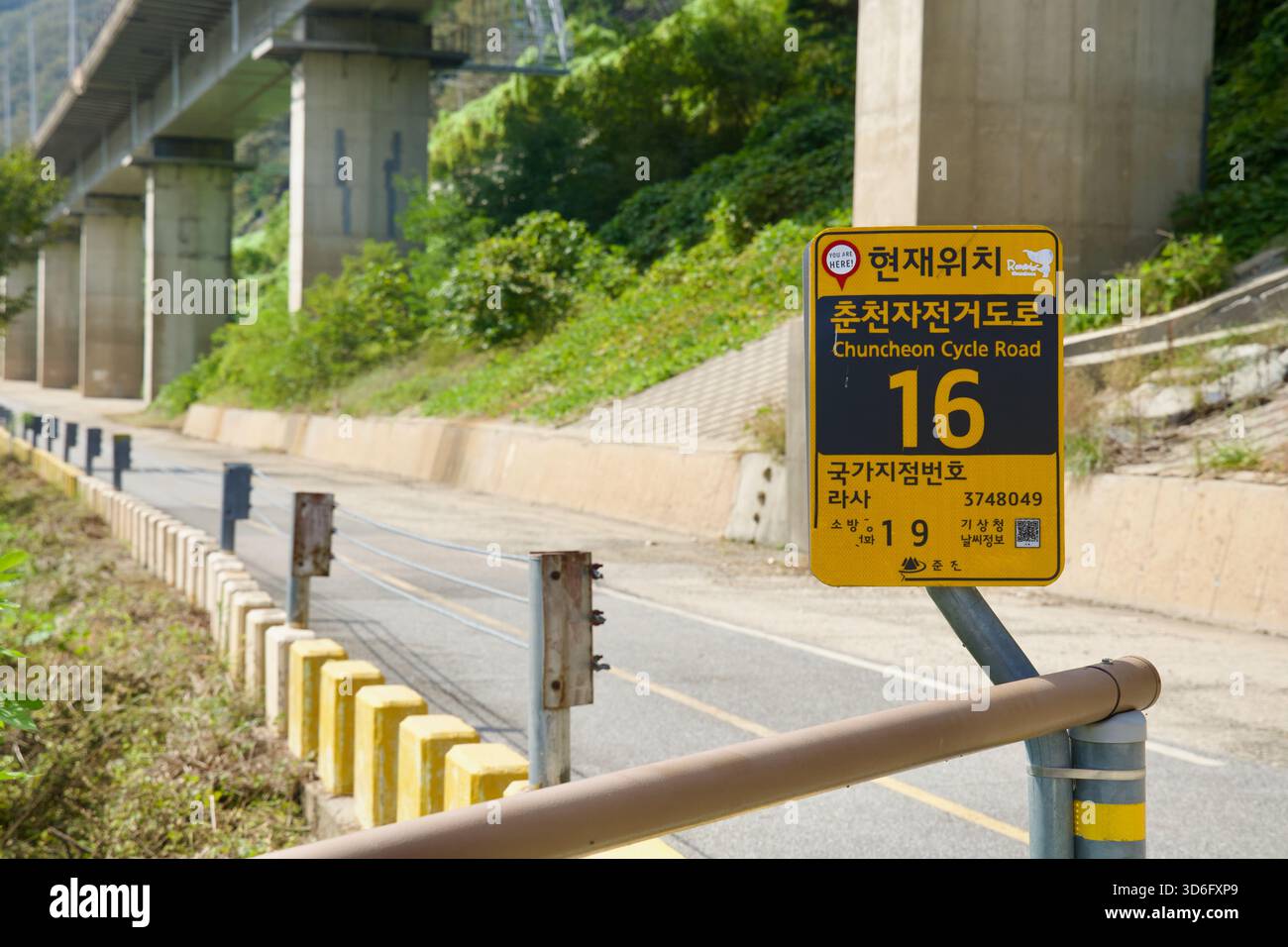 A yellow wayfinding plaque for the Chuncheon Cycle Road marks location ...