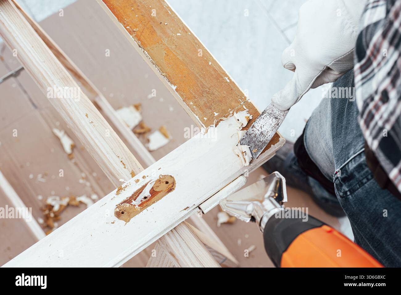 Carpenter using heat gun and wood scraper removes paint from old wooden ...
