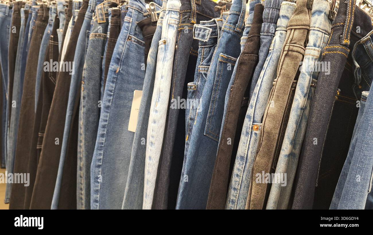 Neatly arranged rack of various denim jeans in different shades and ...