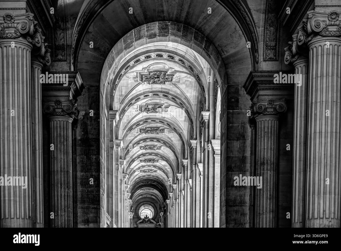 Black and white view of the vaulted stone colonnade at the Louvre ...
