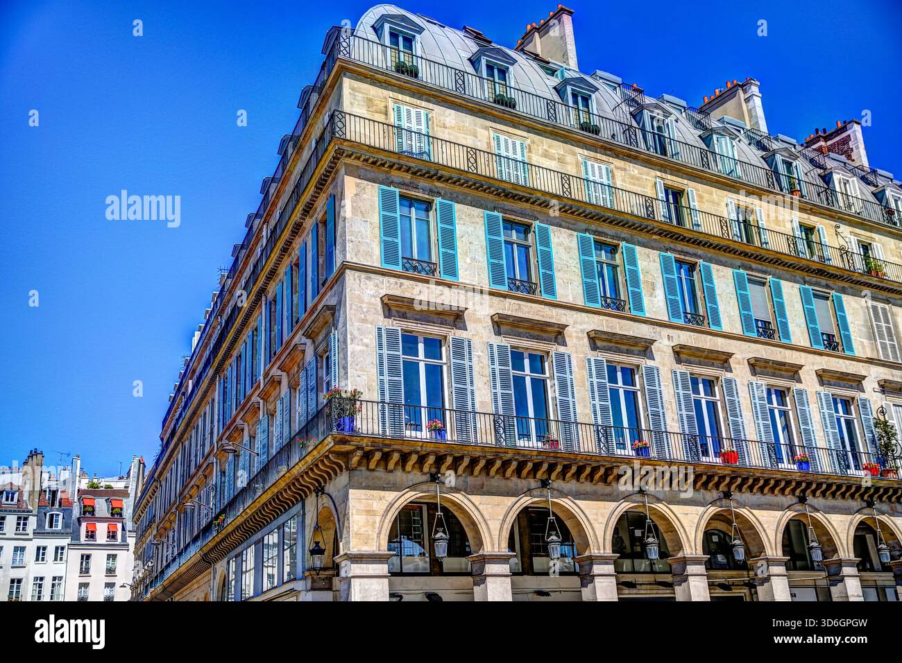 Historic Haussmann-era building with blue shutters and arcades in ...