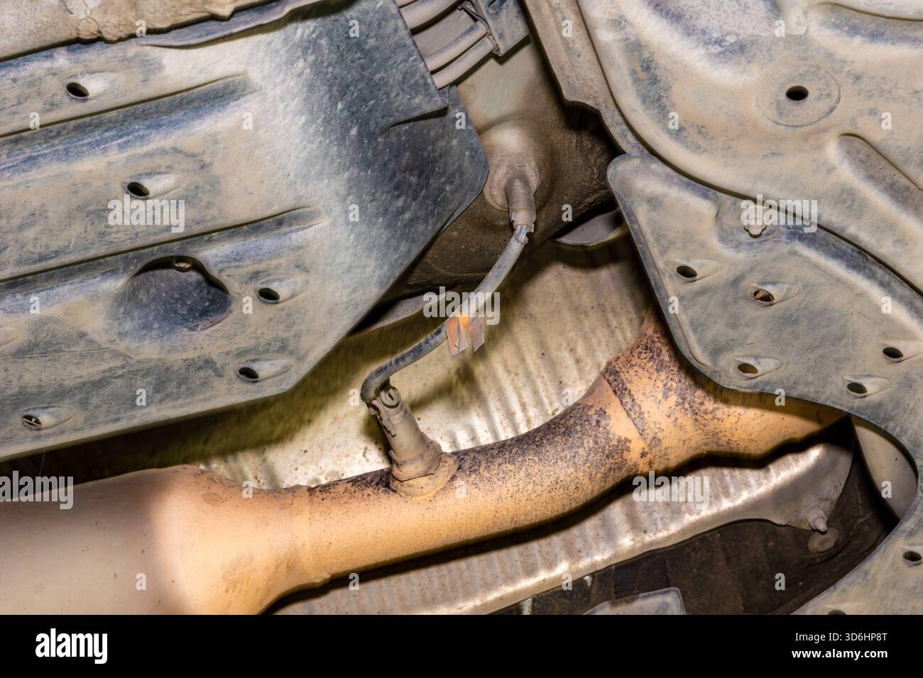 Black plastic undertray and oxygen sensor mounted on sooty exhaust pipe ...