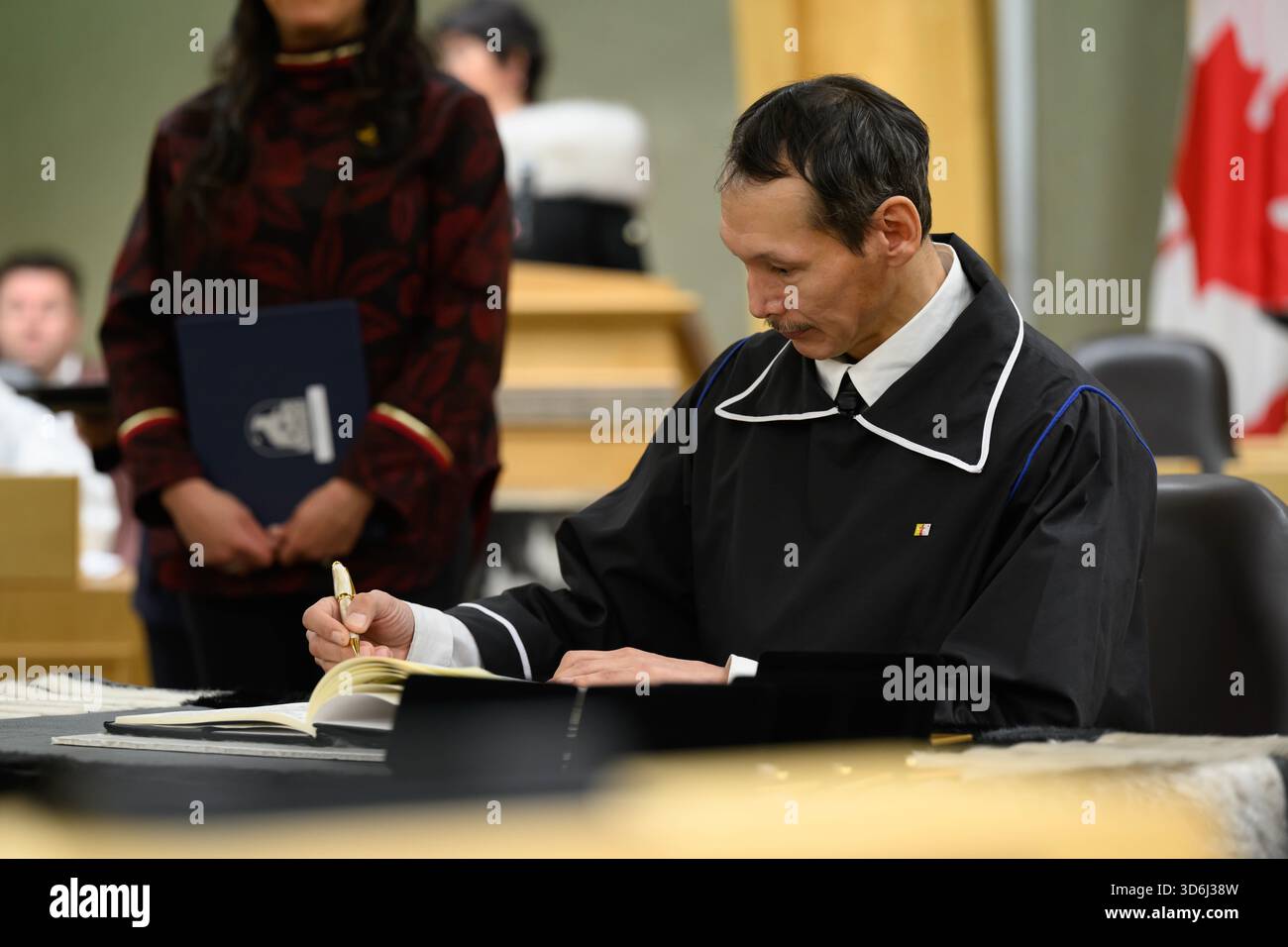 Nunavut Minister of Environment, Brian Koonoo, signs the oath book ...