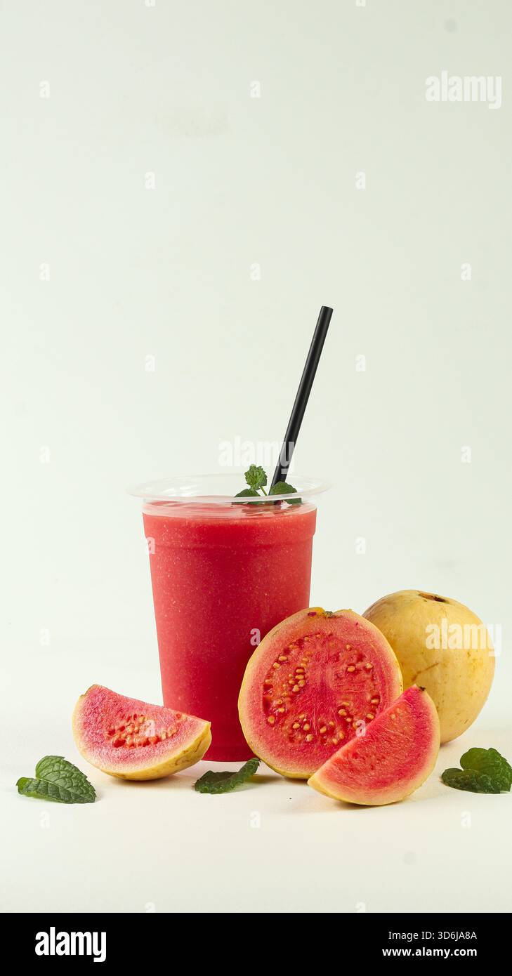 Refreshing guava juice in a plastic cup and straw, accompanied by whole ...