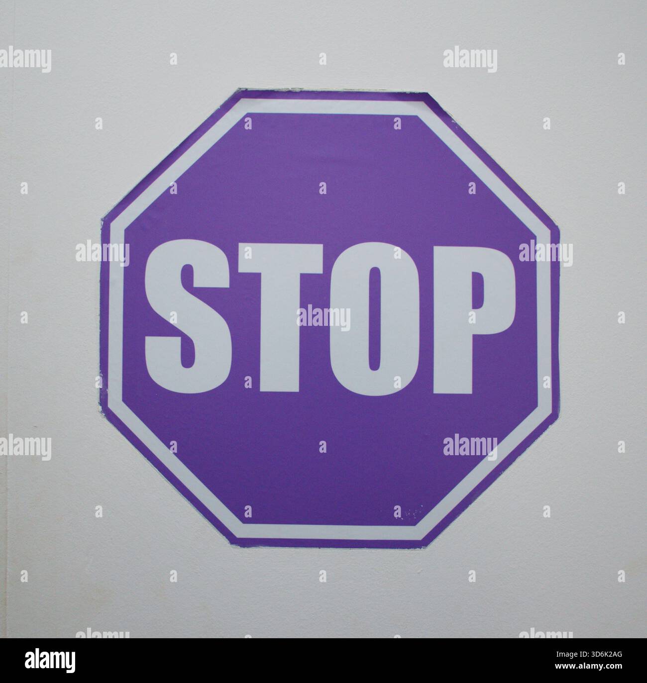 Purple stop sign symbol displayed on a white wall, offering a modern ...