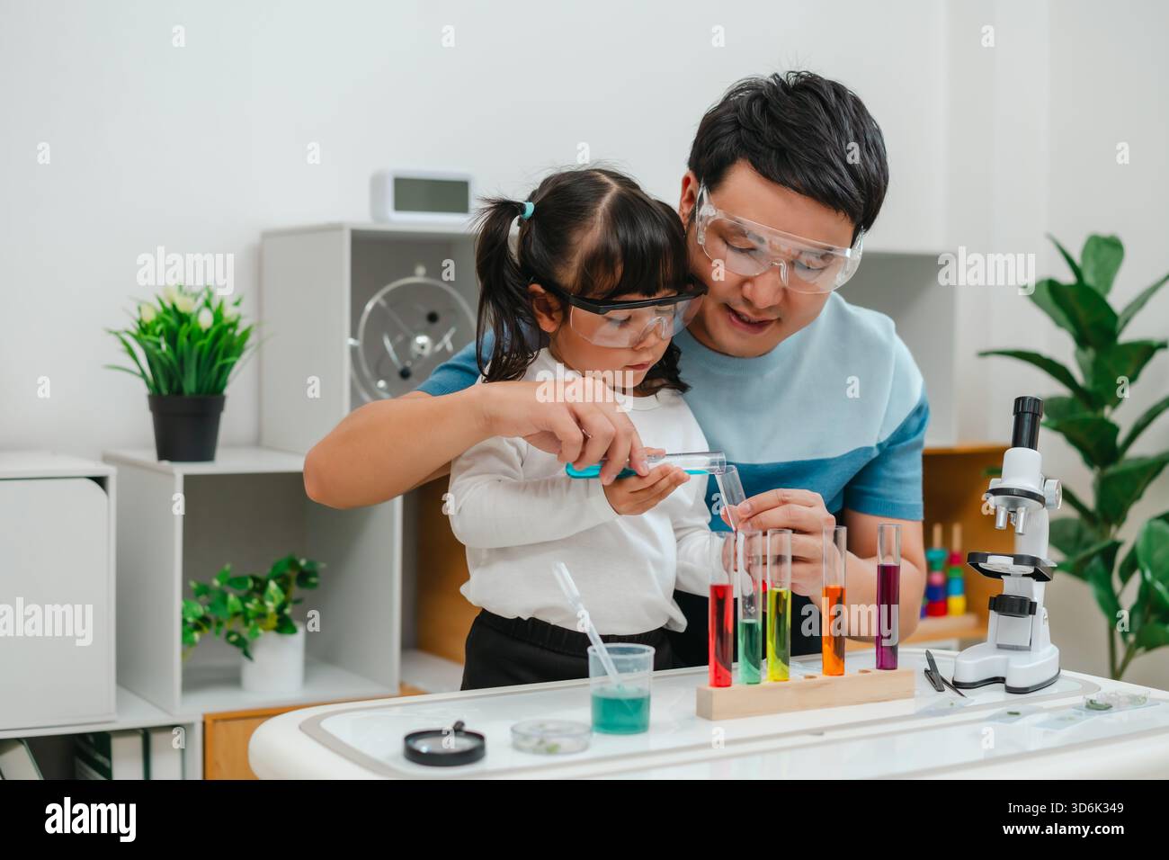 father and toddler girl scientist making chemical test with test tube ...