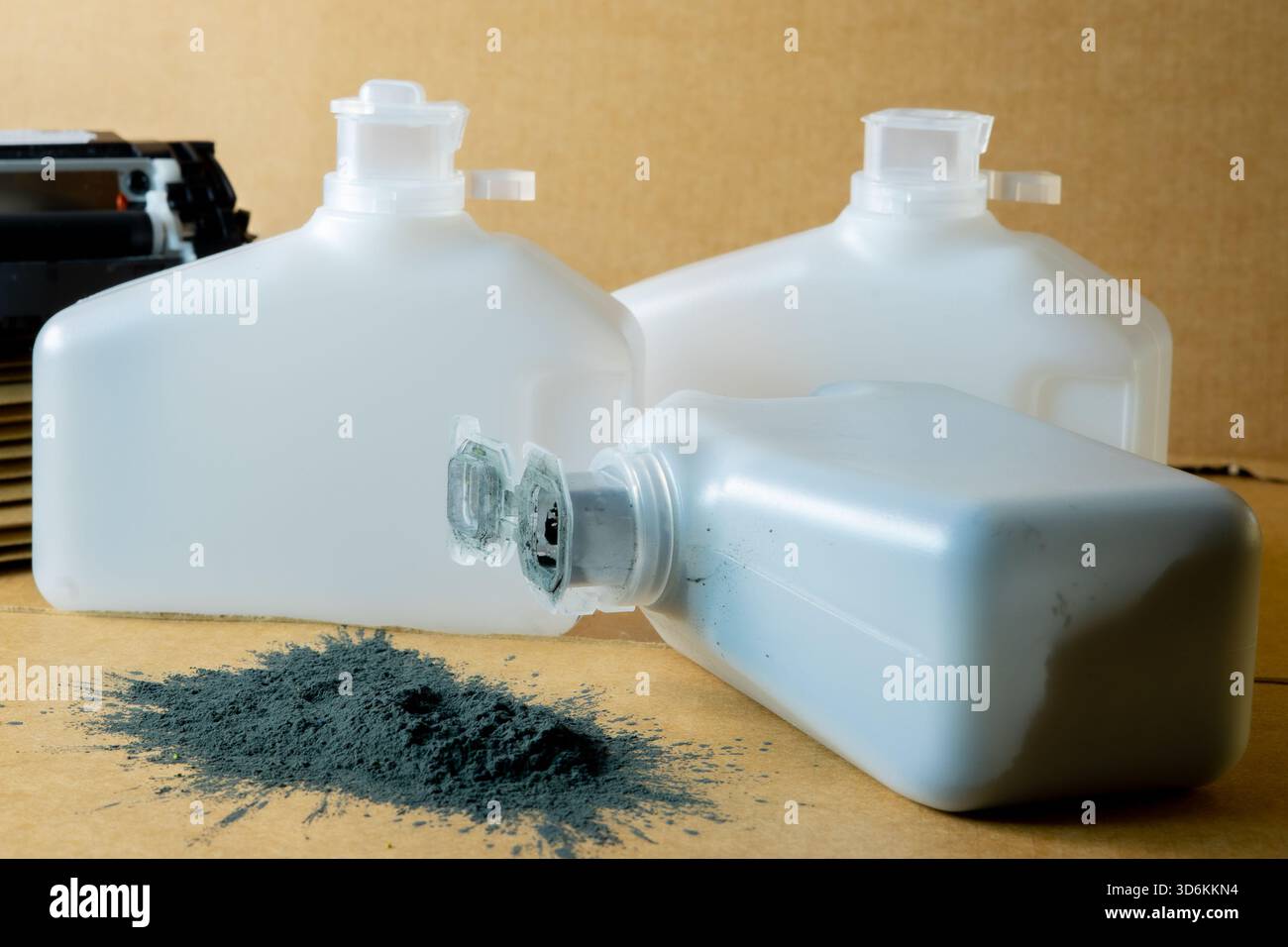 Three white toner refill bottles with spilled black powder on a ...