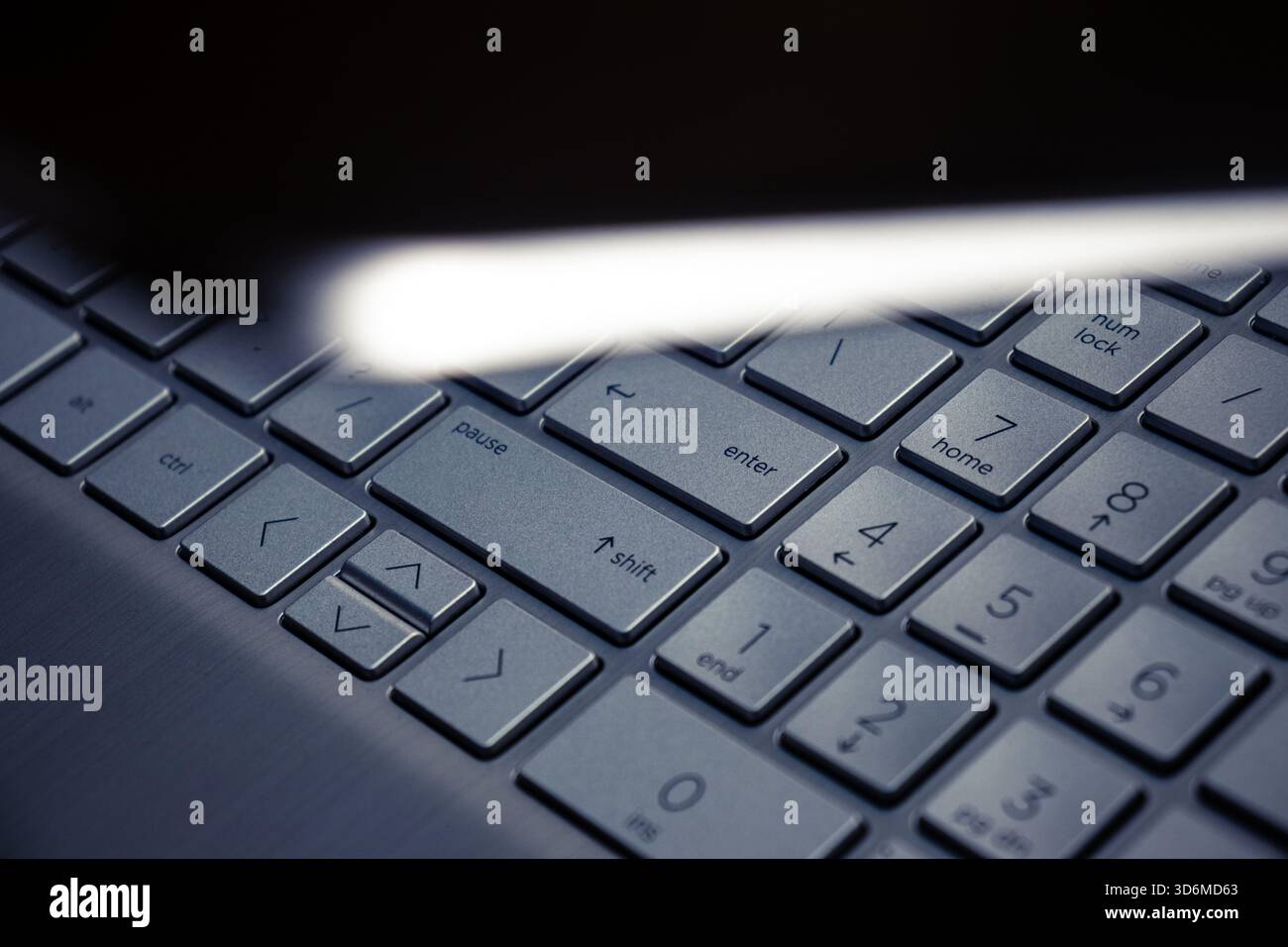 A silver laptop keyboard is viewed from above, partially obscured by a ...