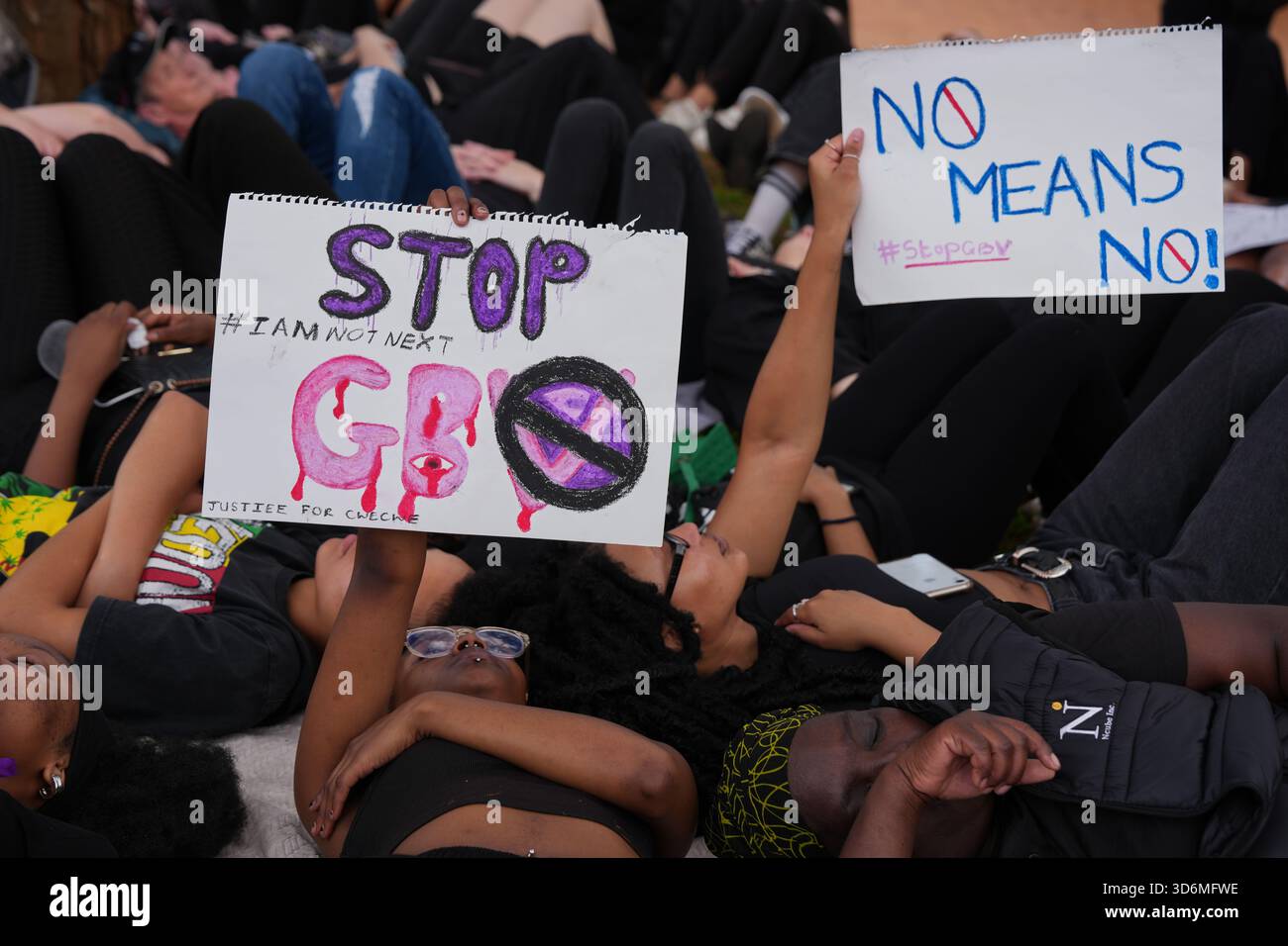 Participants hold signs during a gender-based violence protest at the ...