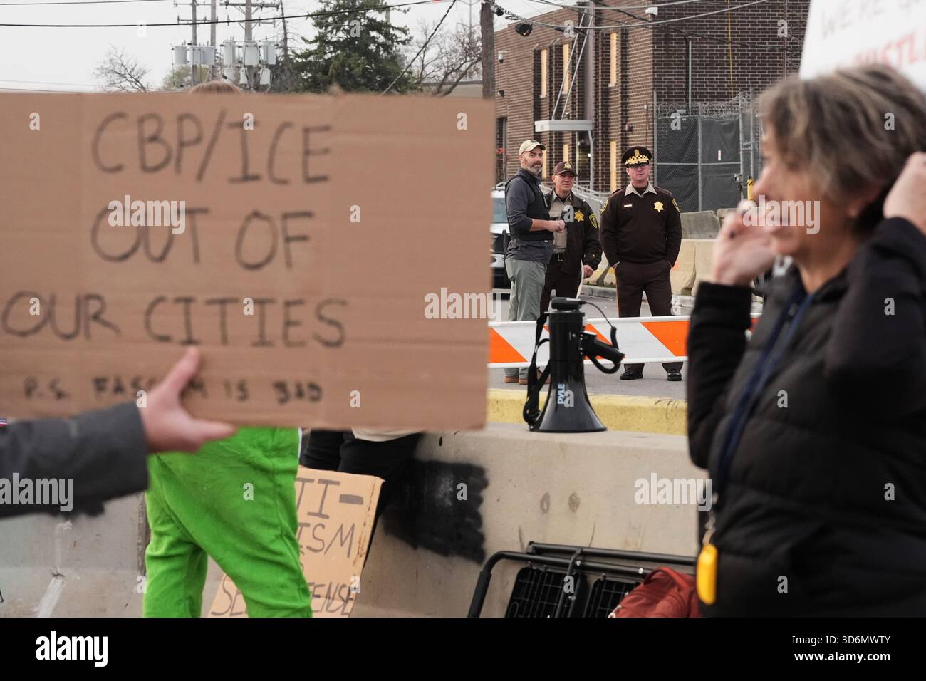Law enforcement officers watch as protesters gather outside an ...