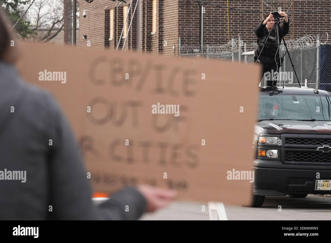 A Law enforcement officer sets up a camera as protesters gather outside ...