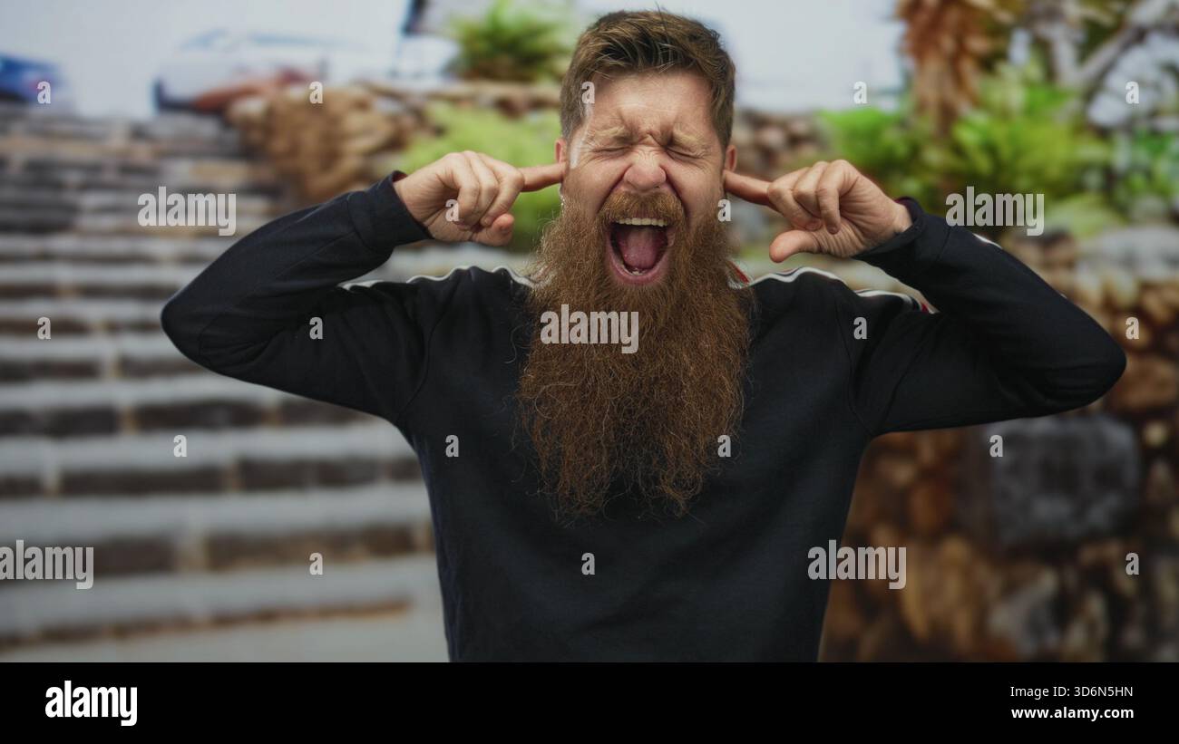 Man with long brown beard covers ears and shouts with open mouth on ...