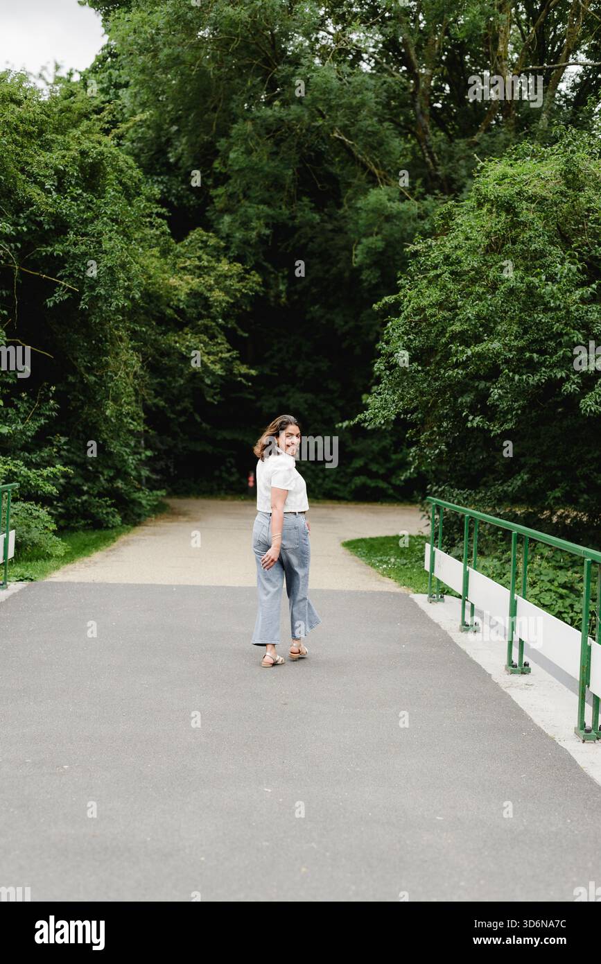 Smiling woman walks turning back toward the camera Stock Photo - Alamy