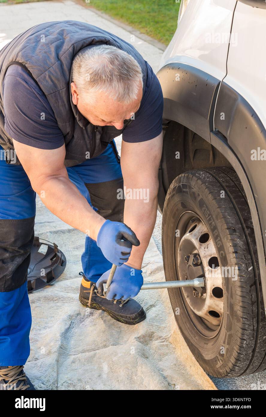 Man unscrewing the wheel bolts to replace a car wheel during a vehicle ...