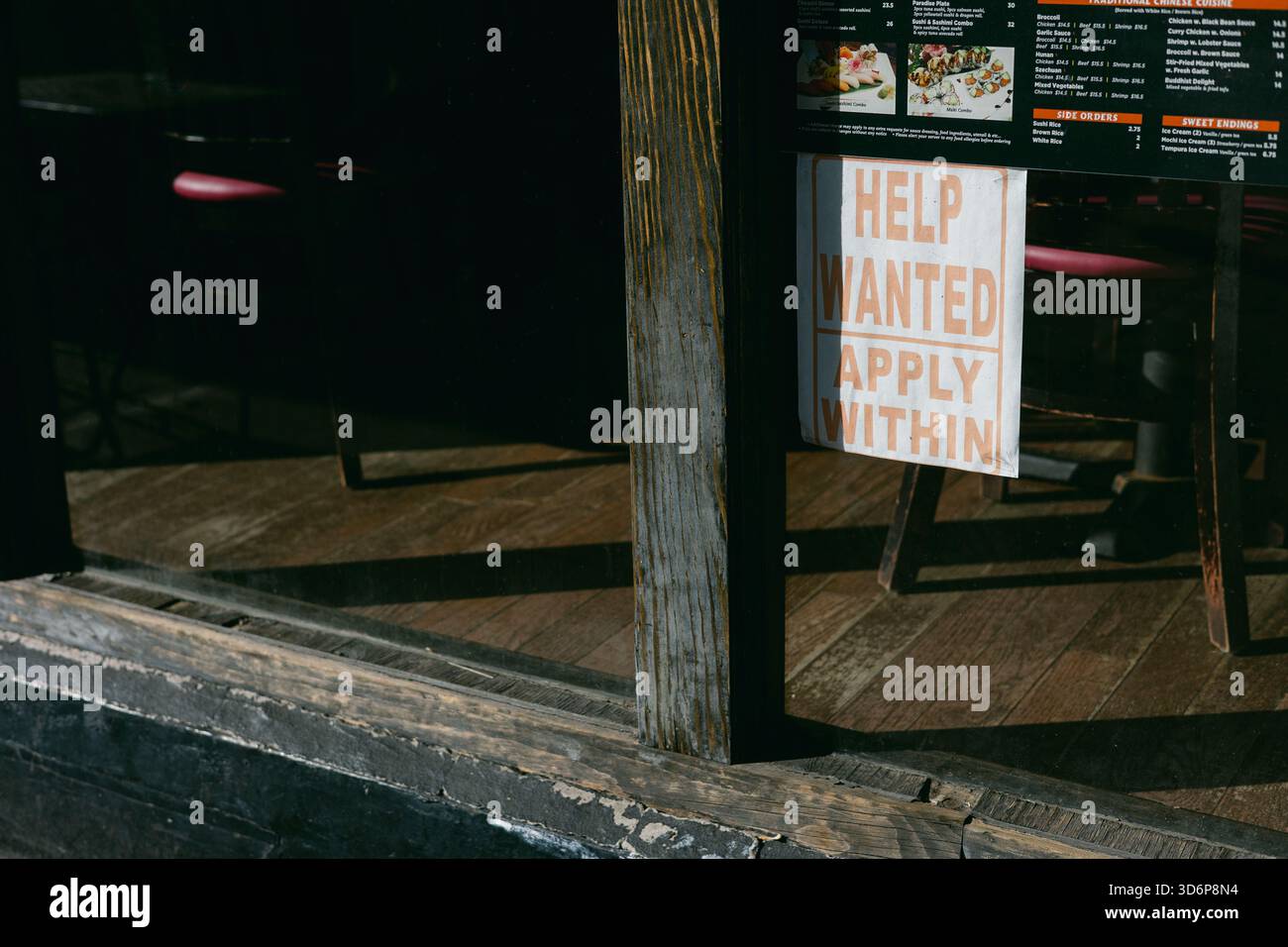 A help wanted sign hangs prominently in a restaurant window, inviting ...