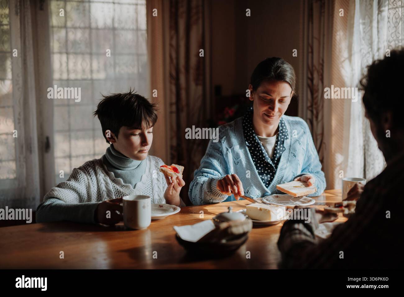 Family having simple meal together, eating bread with jam Stock Photo ...